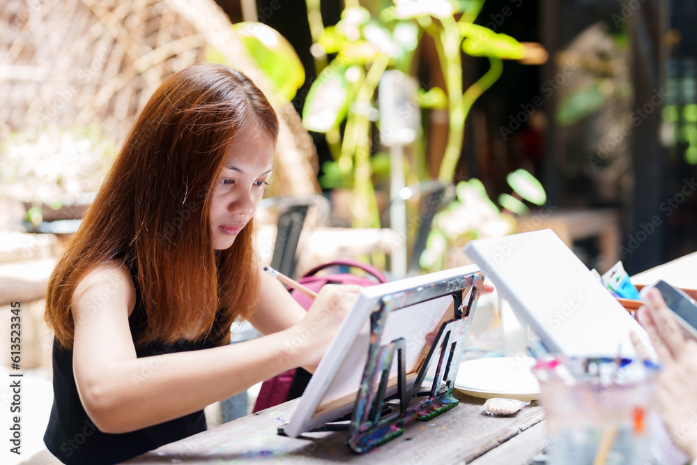Asian girl using paintbrush sitting in the garden practice painting ...