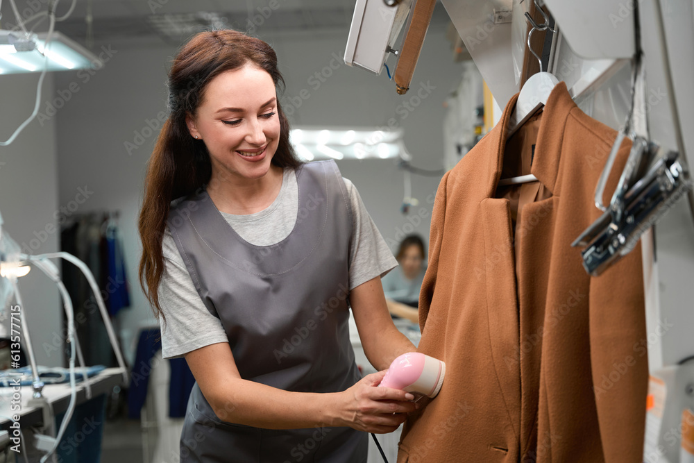 Woman dry-cleaning office worker using lint remover to clean client ...