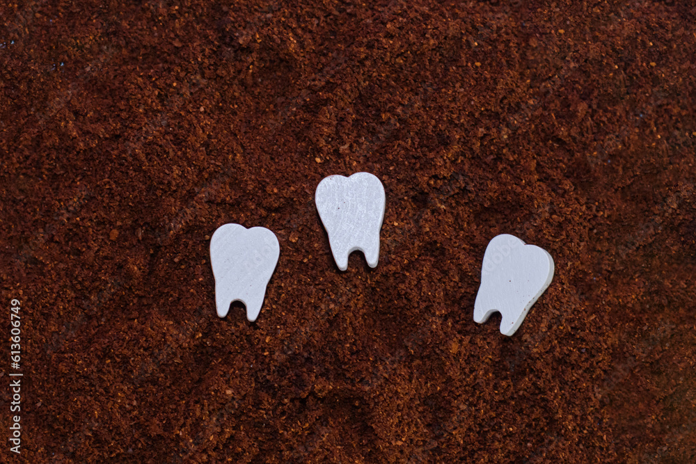 Large white tooth on a pile of roasted coffee beans. Coffee staining ...