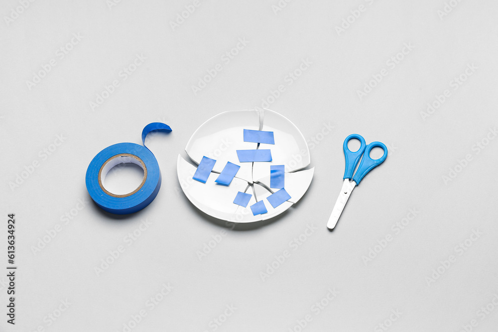 Broken plate with adhesive tape and scissors on light background Stock ...