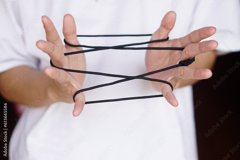 Closeup boy hands is playing rope which called cats cradle game ...