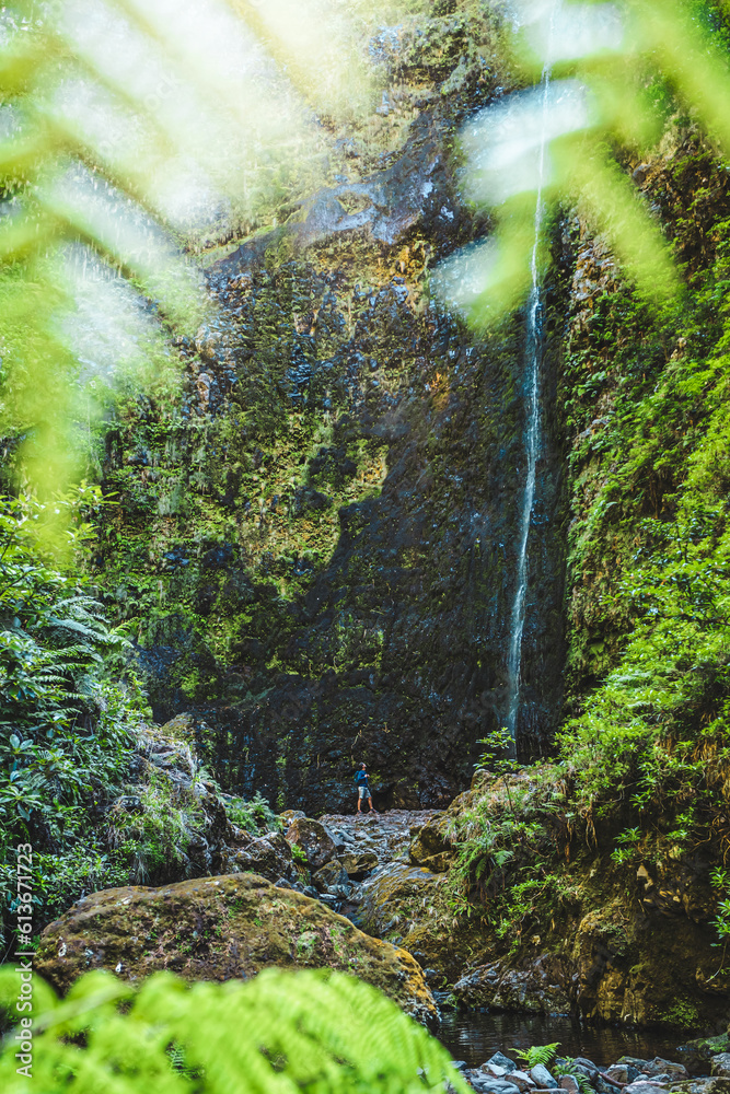 Tourist man in the distance looking at scenic, overgrown waterfall in ...