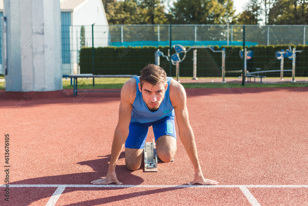 Front view of a Caucasian male sprinter in a race starting position ...