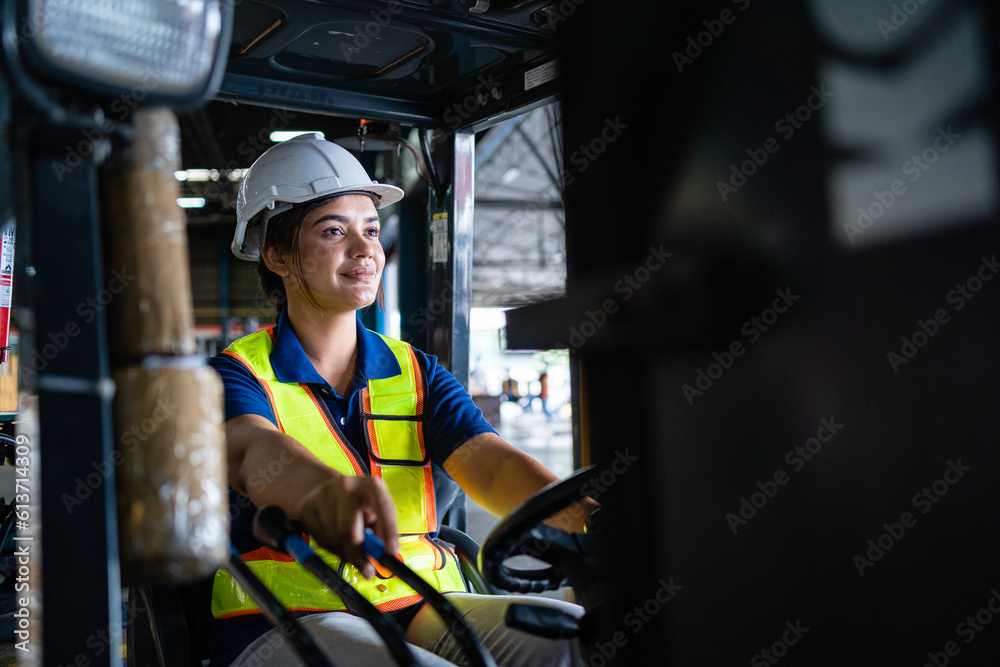 Female factory worker is driving a forklift in a large warehouse. A ...