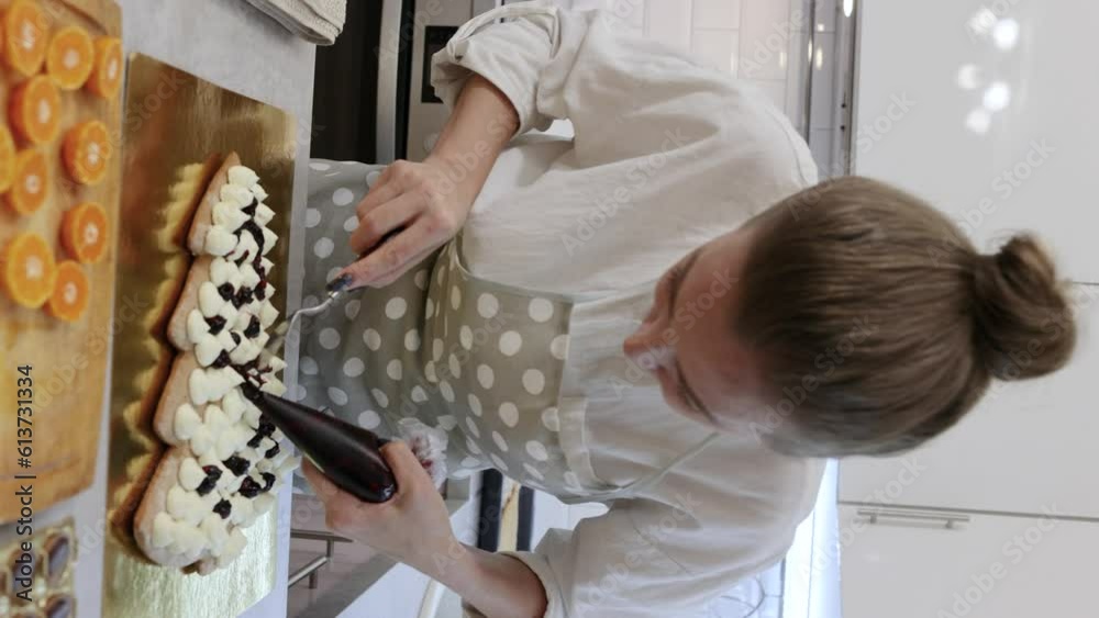 cook a cake in the kitchen. Young female pastry chef cooking a layered ...