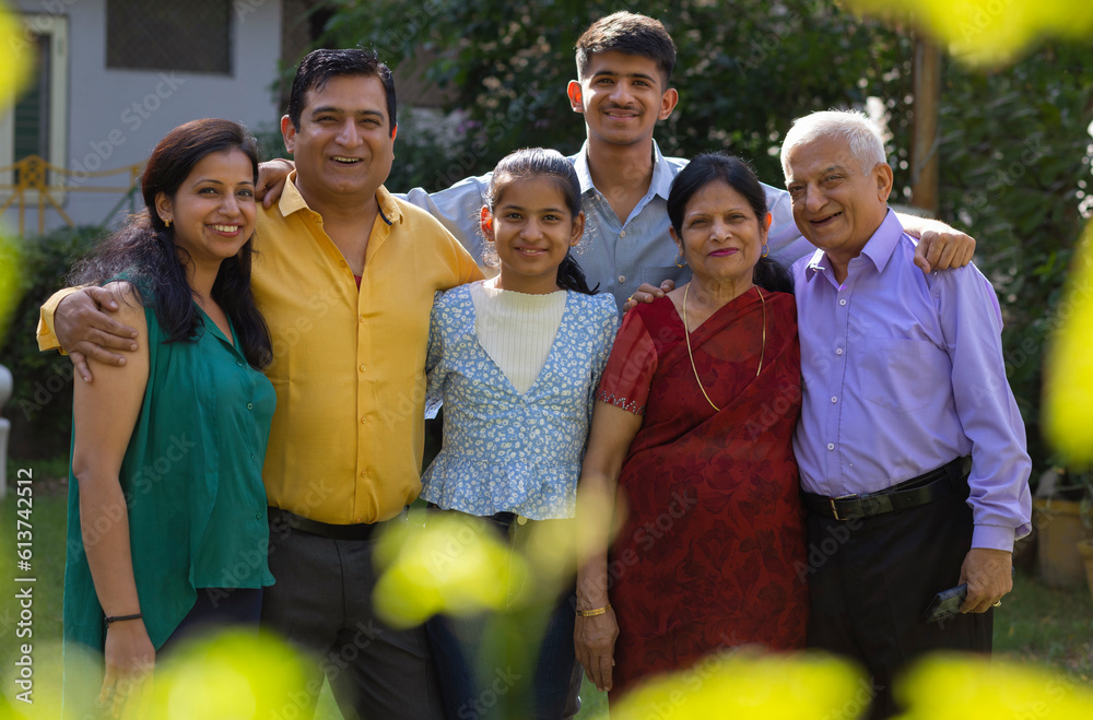 Multi generation happy Indian family standing together in backyard ...