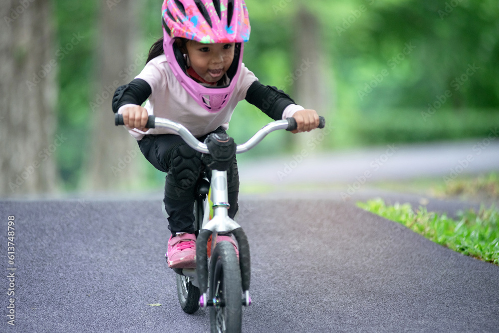 4 years old girl with helmets practicing balance bike, little girl have fun at the pump track ...