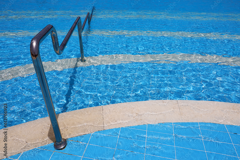 Steps for descending into the swimming pool with a metal handrail ...