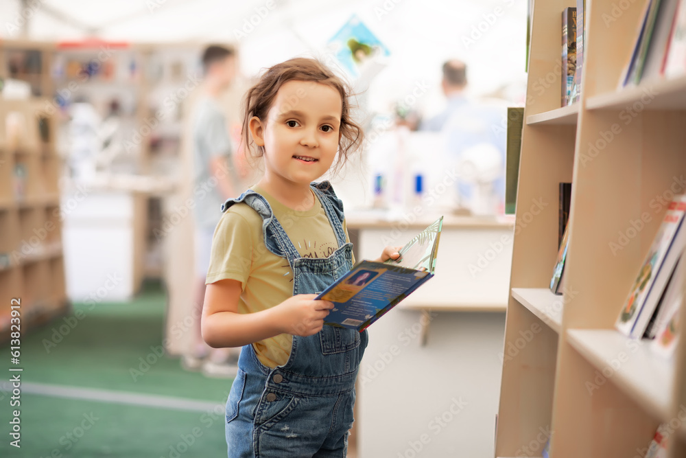 Little cute girl child reading a book on the library or bookstore Stock ...