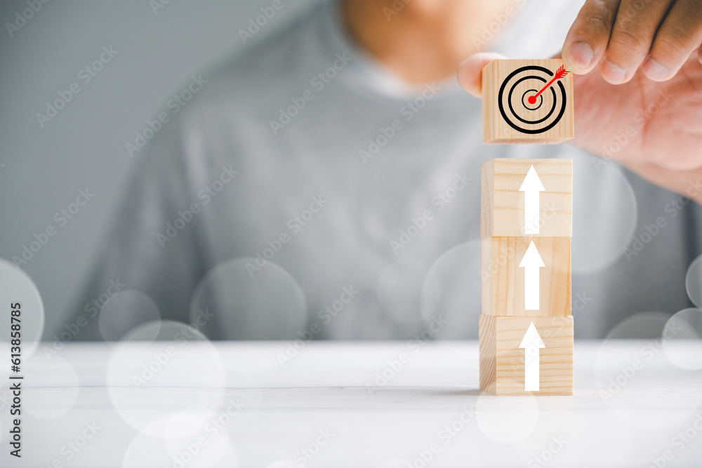 Hand of a businessman arranging wooden blocks in a step-like structure ...
