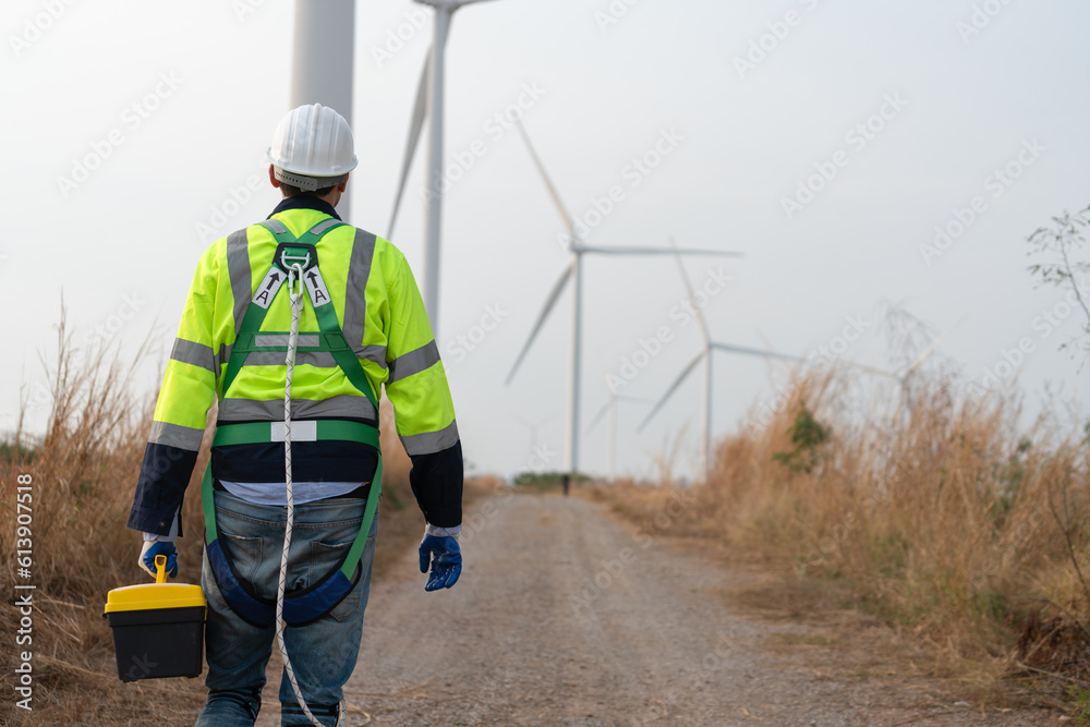 Behind male windmill engineer wearing uniform with helmet safety hold ...