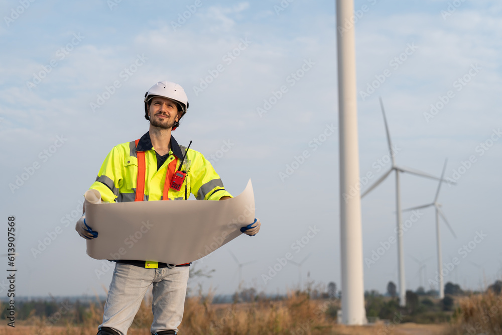 Male windmill engineer in uniform with helmet safety holding blueprint ...