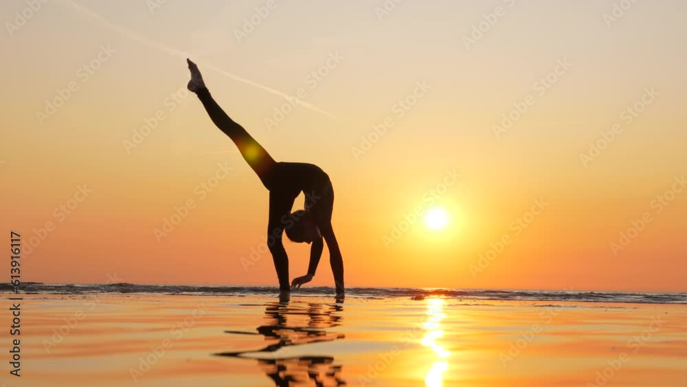 Against backdrop of vibrant sunset, young gymnast girl showcases ...