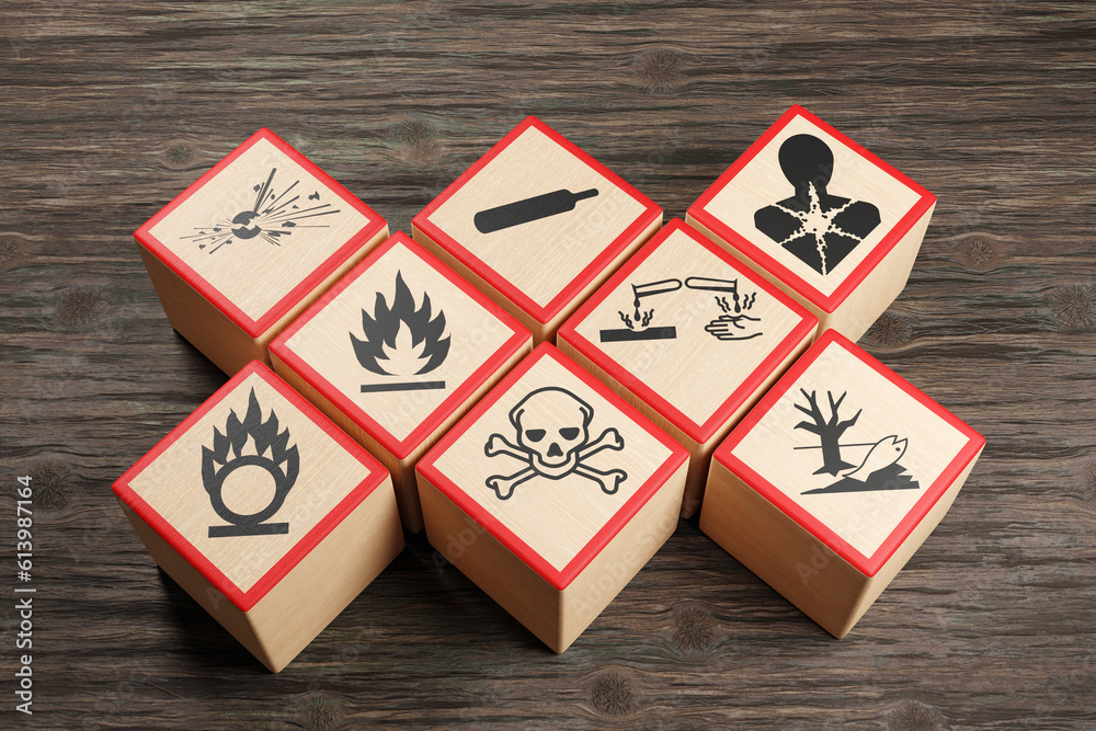Wooden blocks showing different symbols of chemical hazard warnings on ...