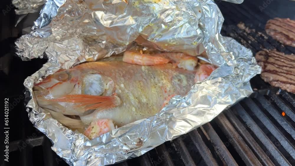 the fish is red and white inside fry red perch fish on foil over an ...