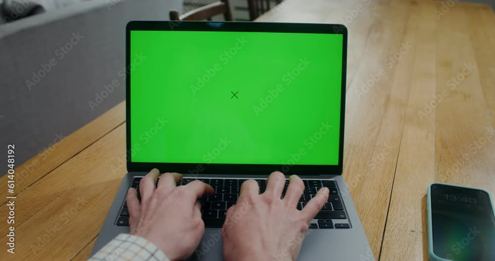 Close-up of a woman's hands while she typing on a laptop with a green ...