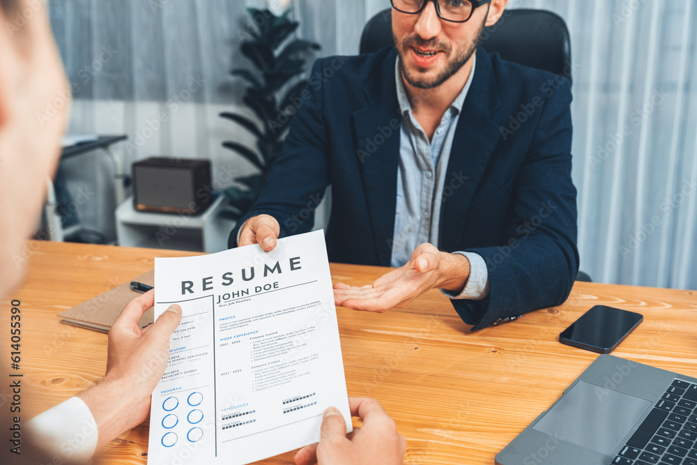 Candidate handing resume or CV over table to interviewer in corporate ...