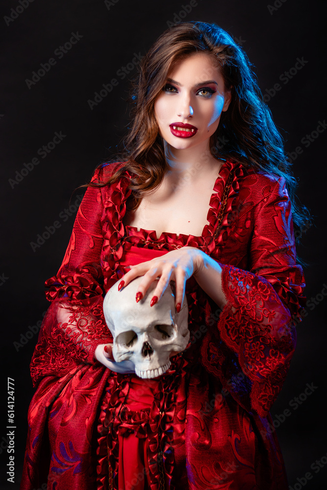 Portrait of a young, attractive vampire woman in a red dress in the ...