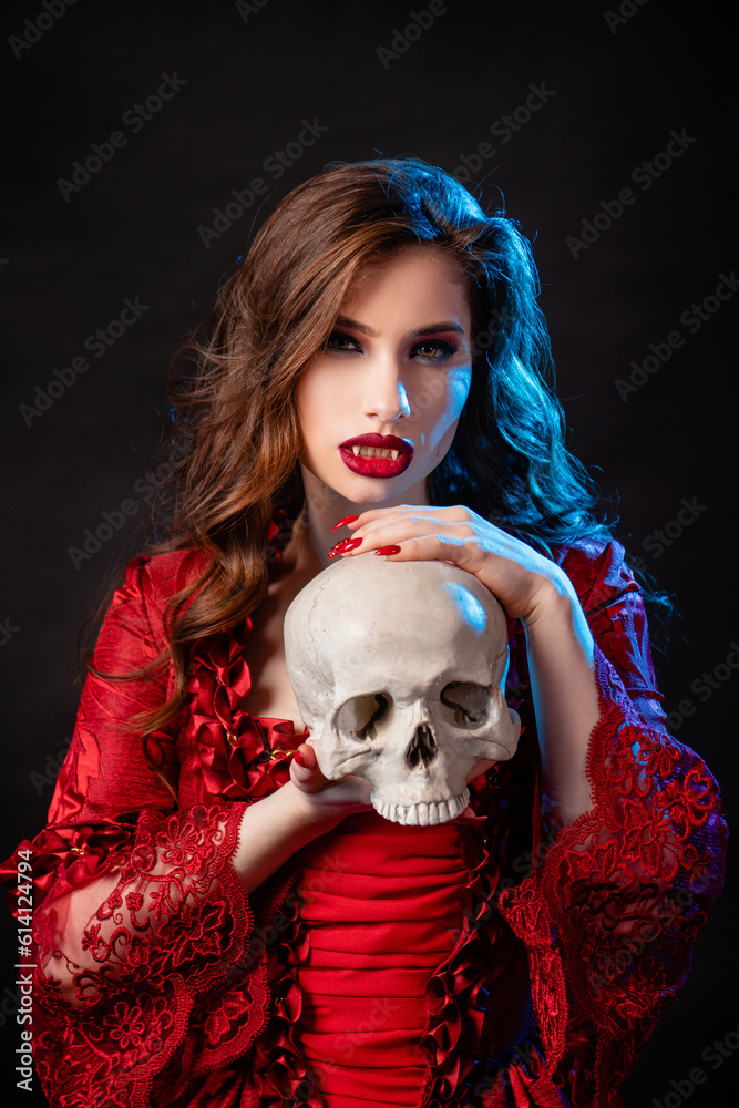 Portrait of a young, attractive vampire woman in a red dress in the ...