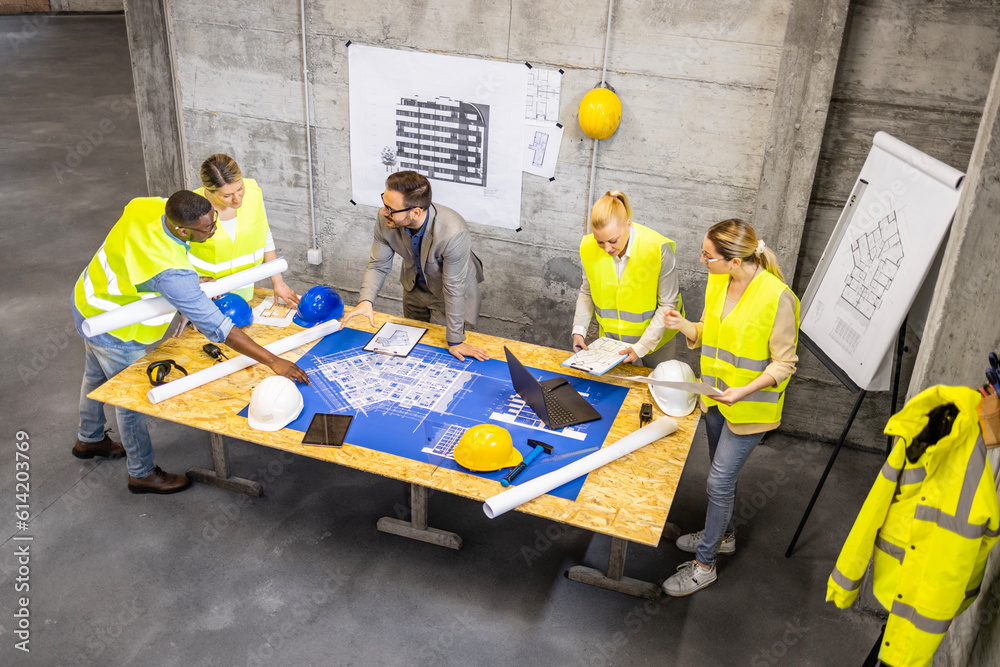 Top view of contractor and architects analyzing plans and blueprints of ...