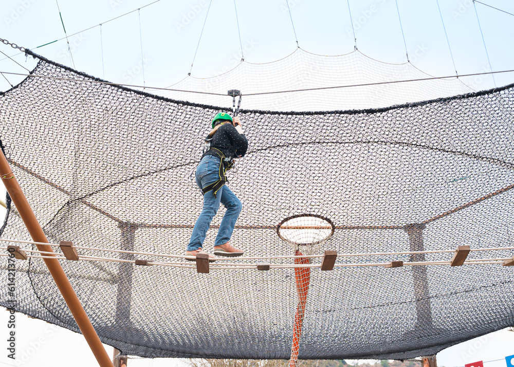 Teenage teen girl in climbing harness equipment, green sports safety ...