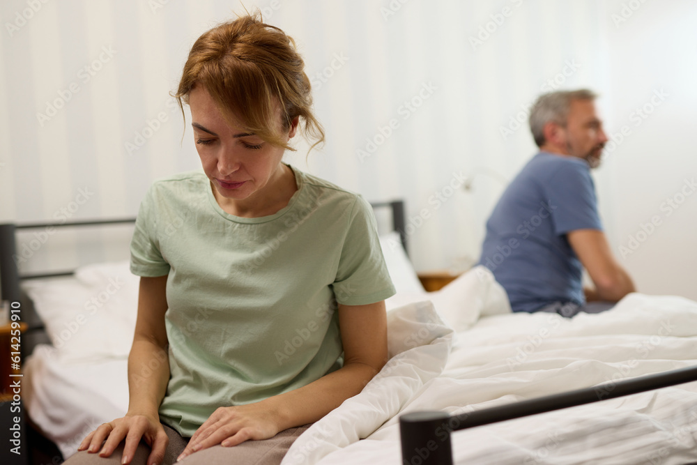 Couple Sitting On Different Sides Of Bed Not Talking After Argument