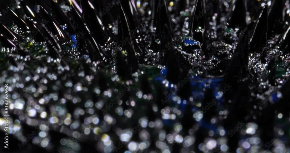 Ferrofluid tinted with colored paints. The surface of the black, blue ...