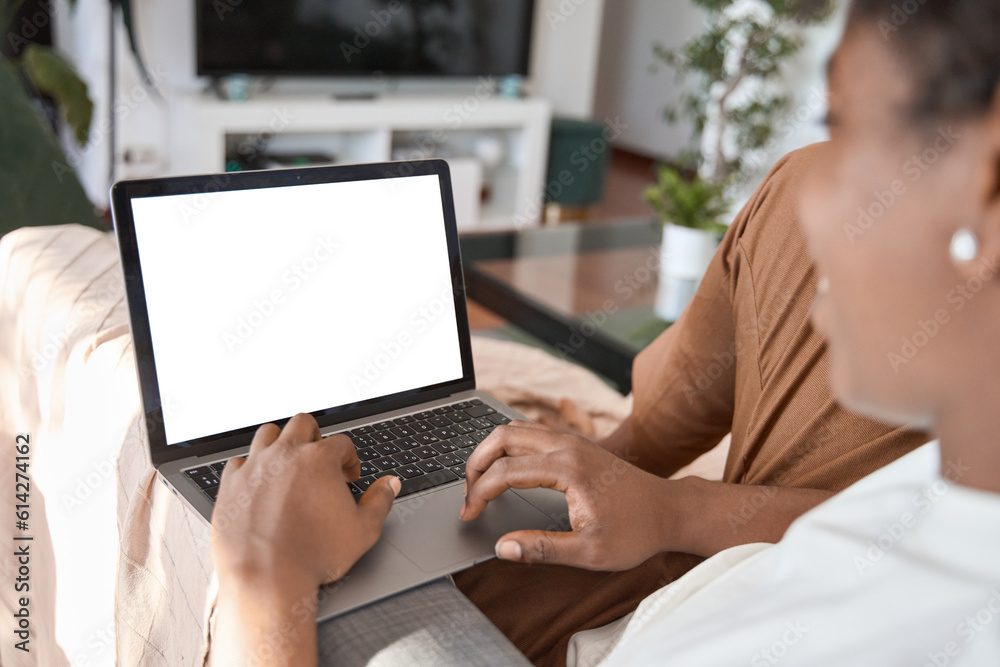 Over shoulder view of relaxed gen z African American teen holding laptop mock up white pc screen ...