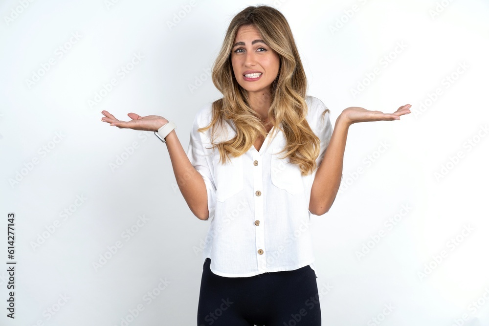 Clueless young beautiful woman wearing white shirt over white studio ...