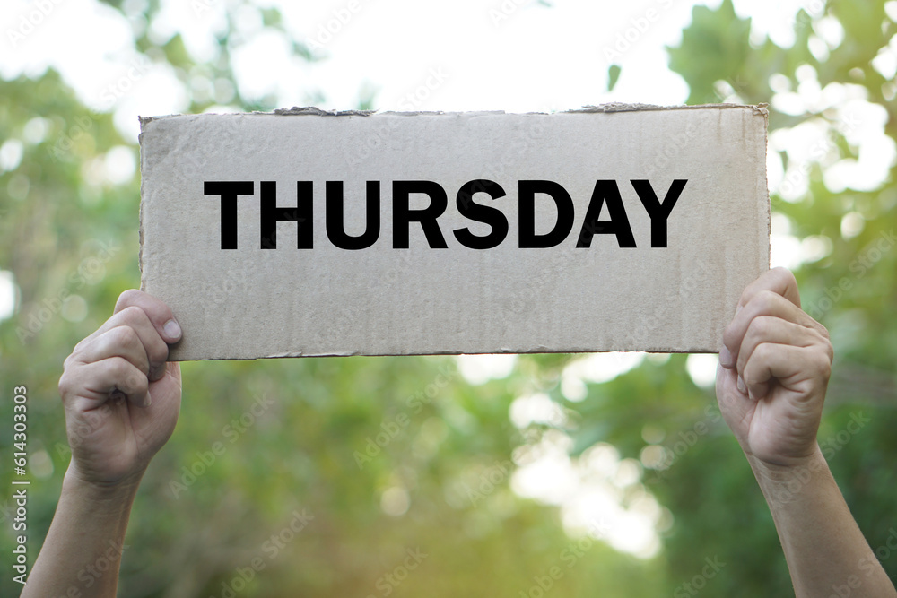 Hands hold word card for teaching with word THURSDAY. Concept, language ...