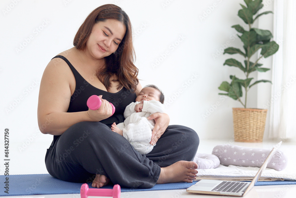 Plump mother doing exercises while watching online tutorial on laptop ...