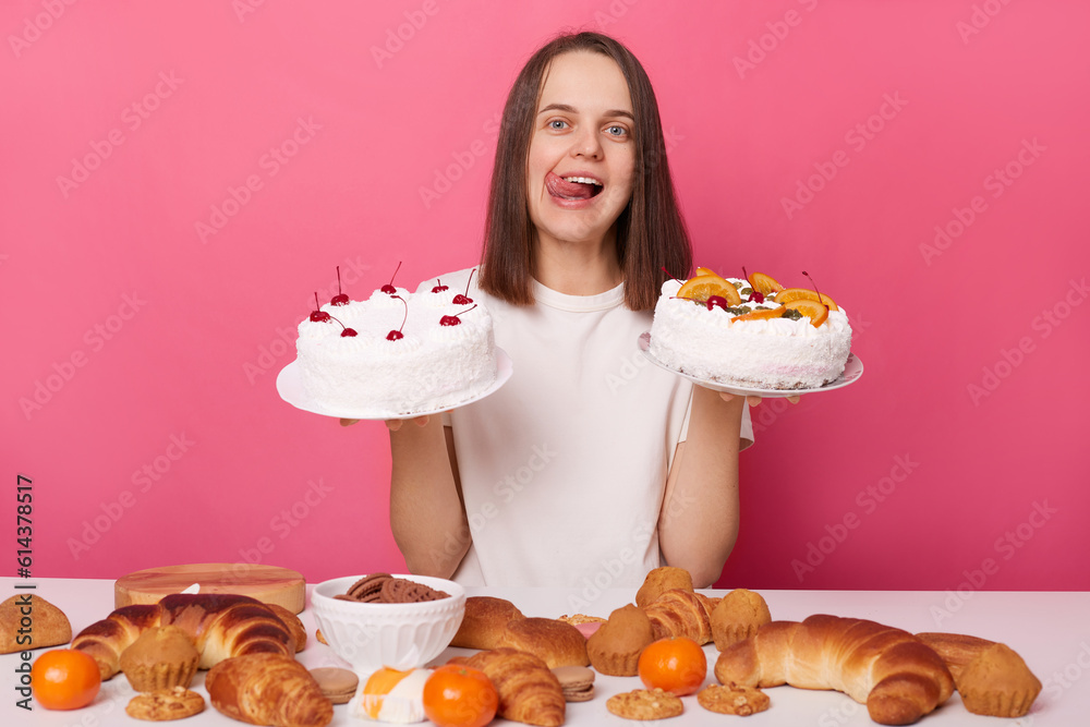 Hungry girl posing at table with sugary desserts and bakery isolated ...