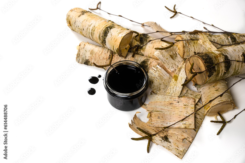 Birch tar or pitch in a jar and birch tree bark on white background ...