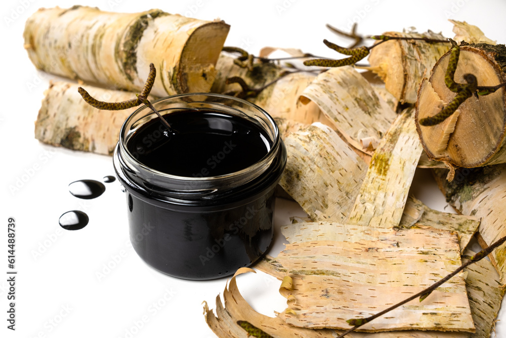 Birch tar or pitch in a jar and birch tree bark on white background ...