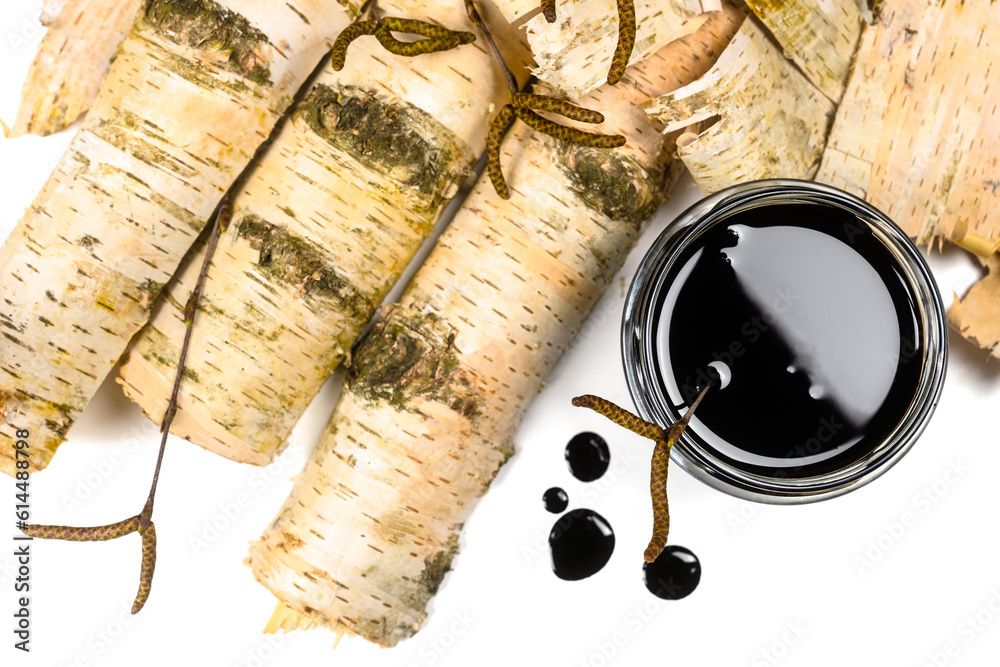 Birch tar or pitch in a jar and birch tree bark on white background ...
