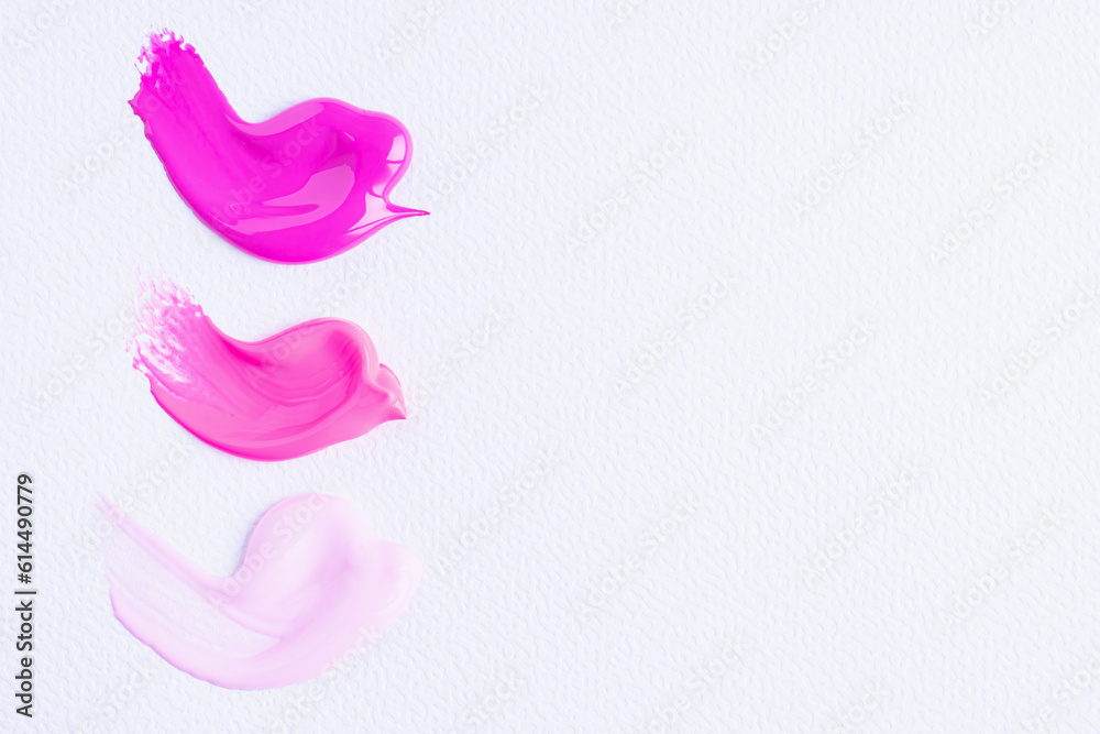 Three smears of different pink paint swatch on white paper background ...