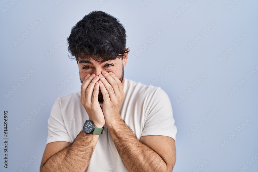 Hispanic man with beard standing over white background laughing and ...