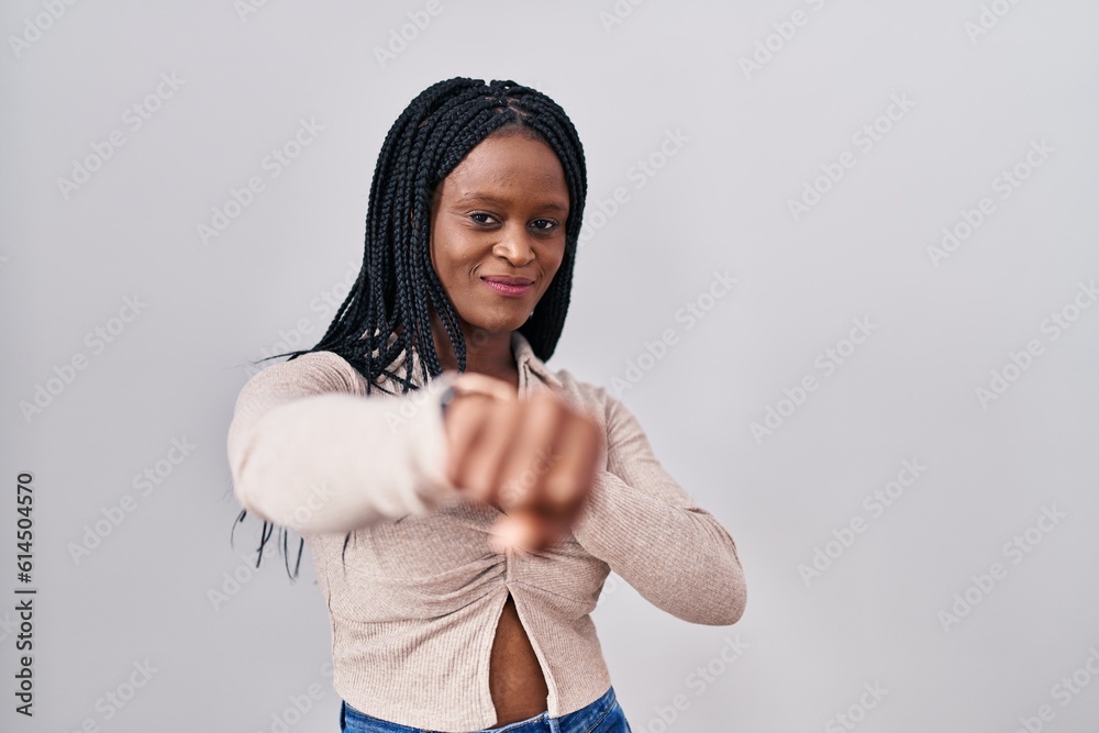 African woman with braids standing over white background punching fist ...