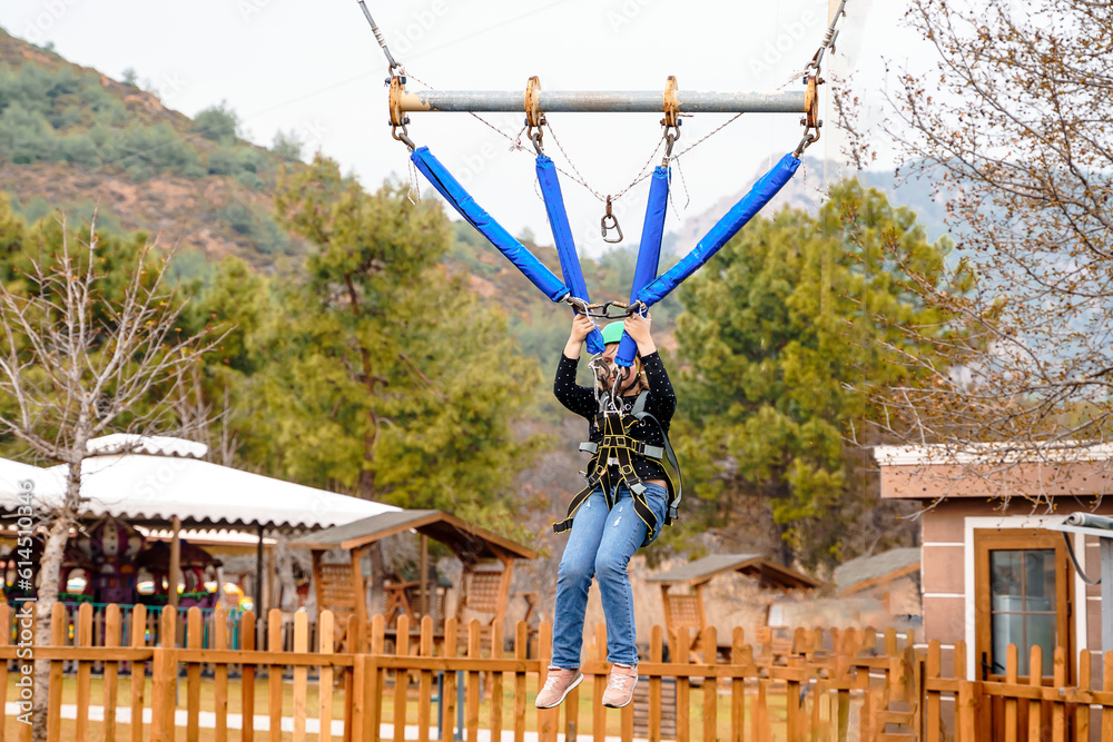 Teenage teen girl bungee flying in rope amusement park. Climbing ...