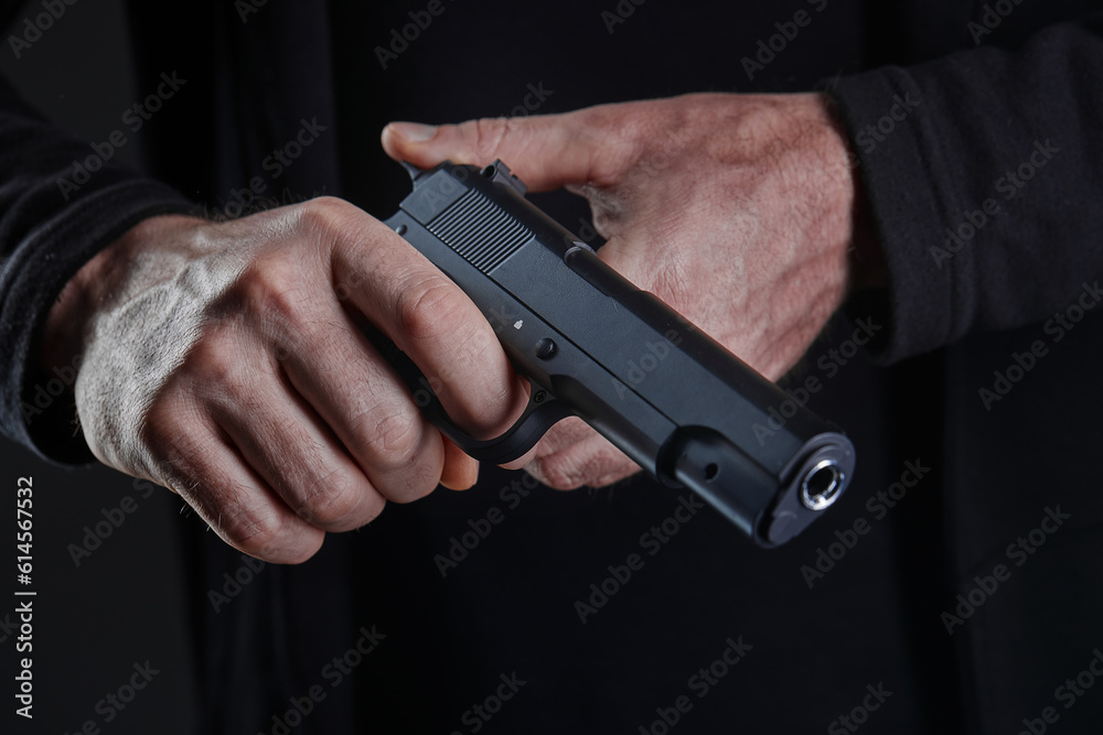 Male hand holding a gun on black background . A gun in a man's hand ...