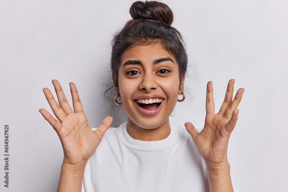 Positive Indian woman keeps palms raised and mouth wide open reacts ...