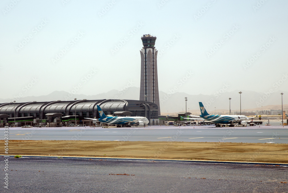Muscat airport control tower. Oman Air planes at the boarding gates of ...
