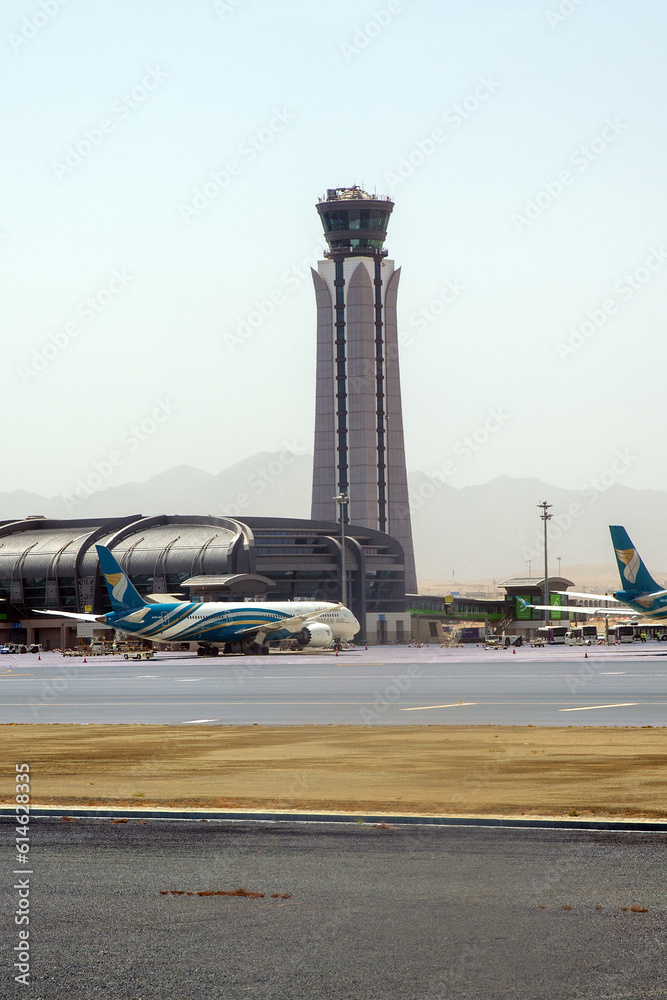 Muscat airport control tower. Oman Air planes at the boarding gates of ...