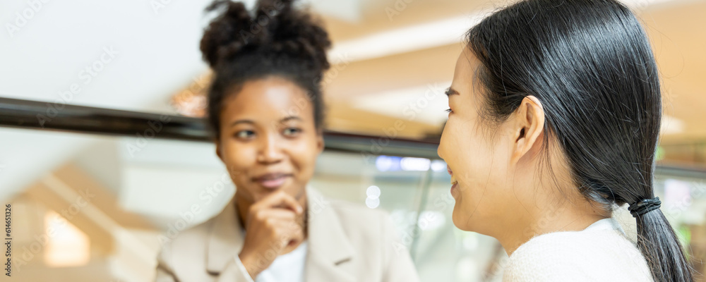 Asian woman talking fluently with her African friend or co-worker ...