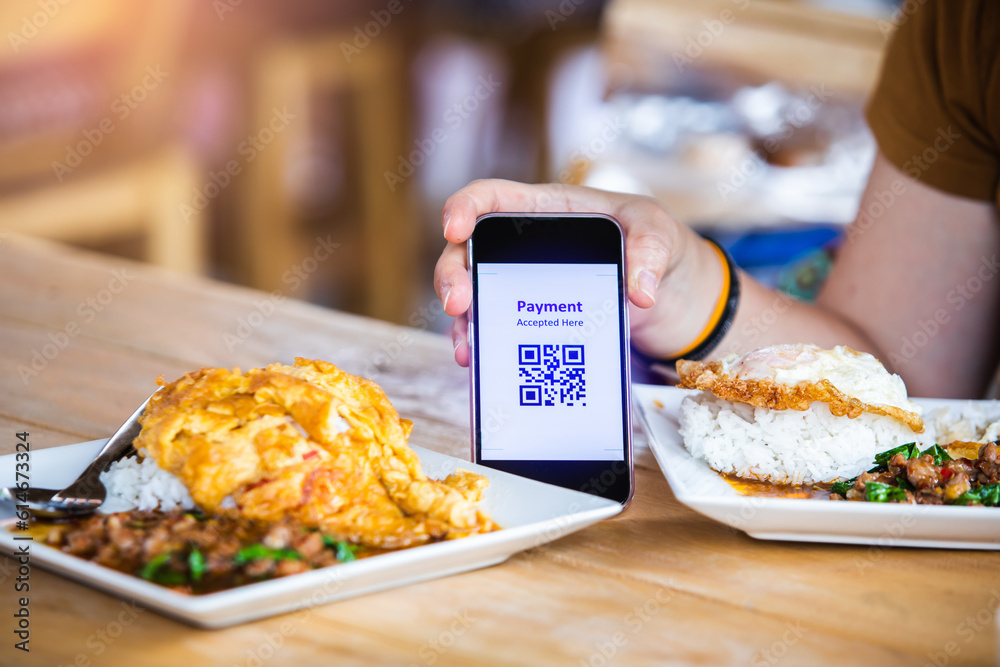 QR code payment tag on smartphone with blurry pork basil stir-fry with ...