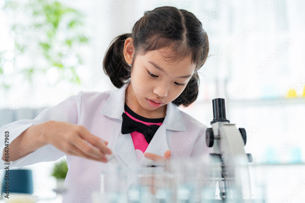 Cute little girl wear lab coat and using syringe to suck the green ...