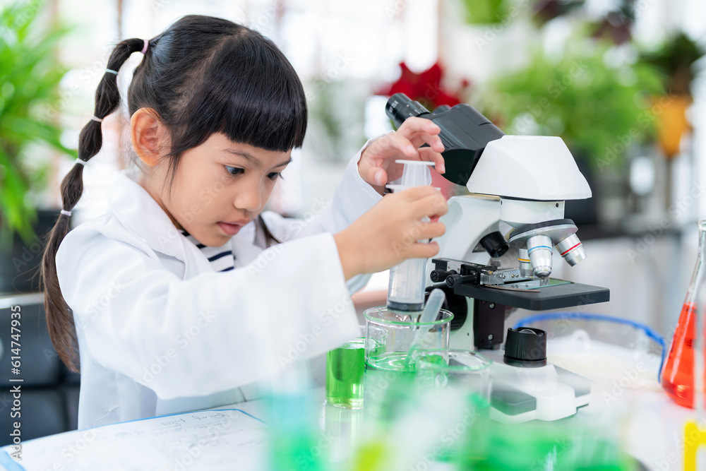 Cute little girl wear lab coat and using syringe to suck the green ...