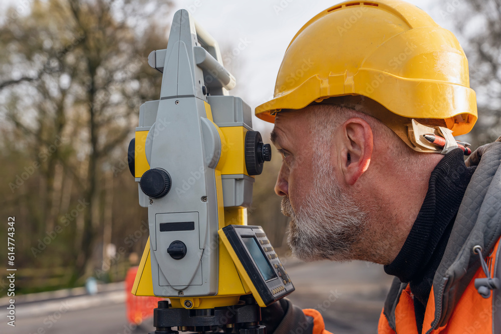 Site engineer operating his instrument during roadworks. Builder using ...