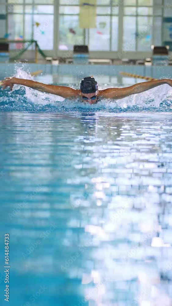 Vertical video of front view of a female swimmer swimming butterfly ...