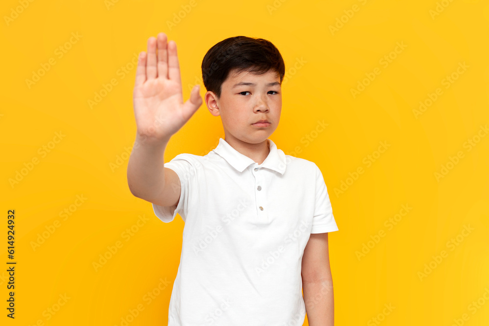 little asian boy showing palm and stop gesture on yellow background ...